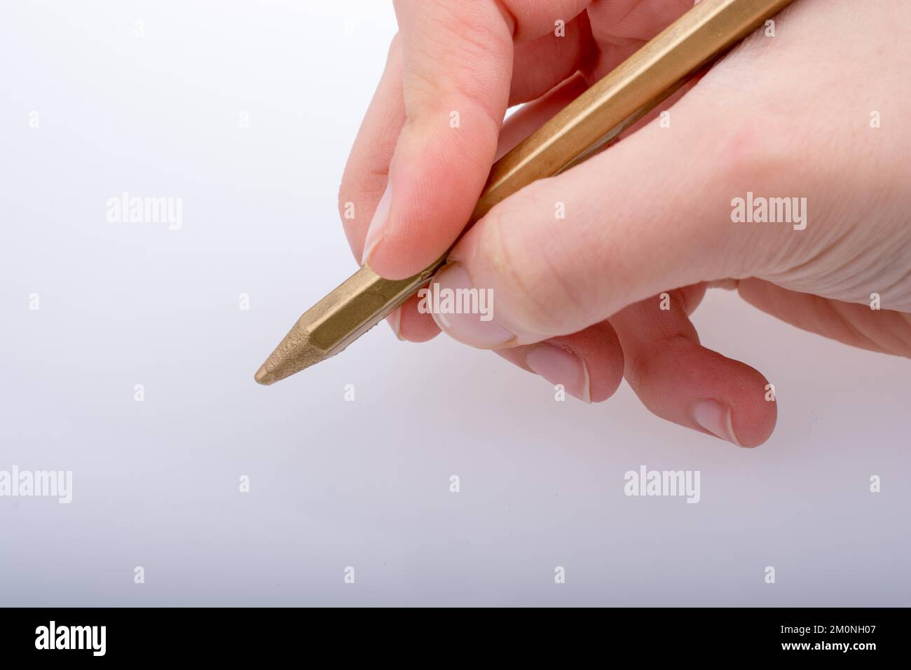 Hand holding a gold color pencil on a white background Stock Photo - Alamy