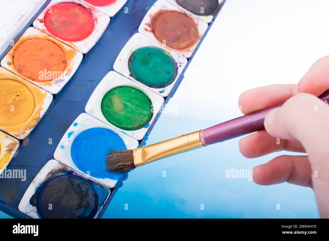 Watercolor paint dissolving in water as painting brush touches water ...