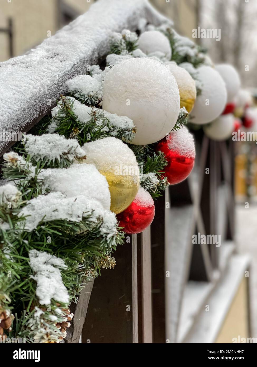 snow-covered Christmas tree decorations on the fence in winter Stock ...