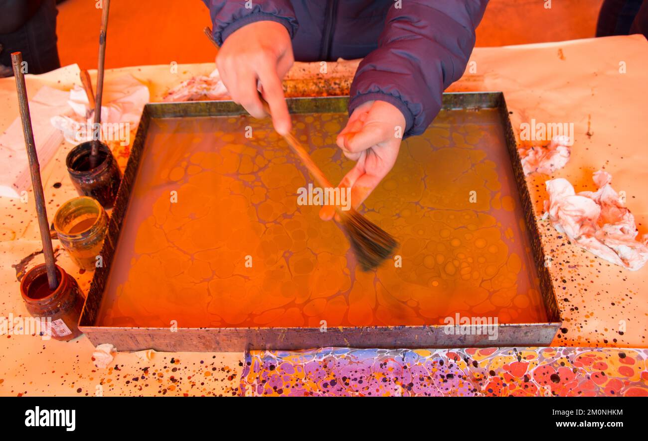 Hand splashing paint over water surface in marbling Stock Photo - Alamy