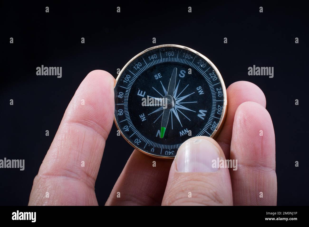 Child hand holding a compass on a black background Stock Photo - Alamy