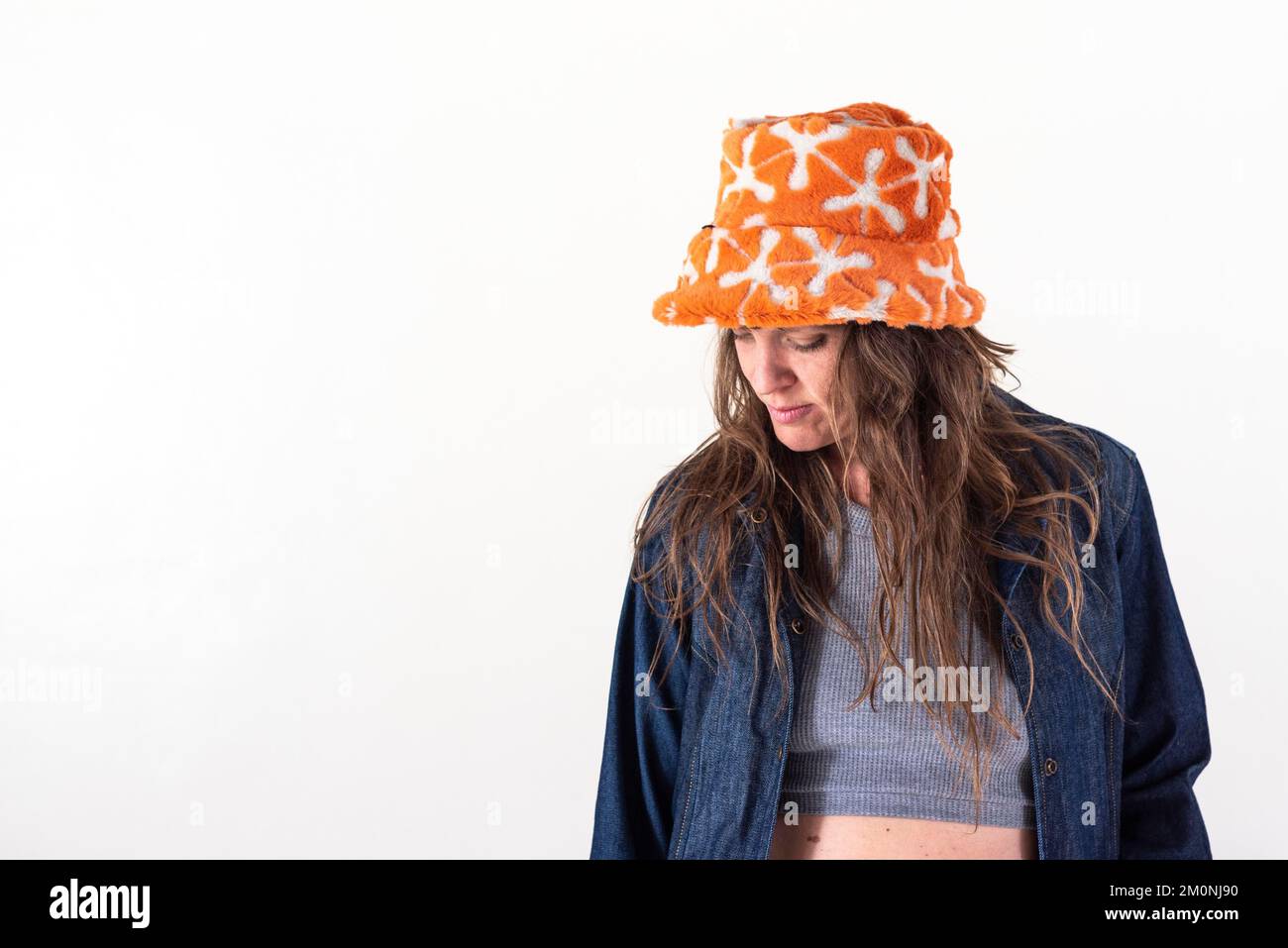 Portrait of a woman looking down, wearing a hat over a white background ...