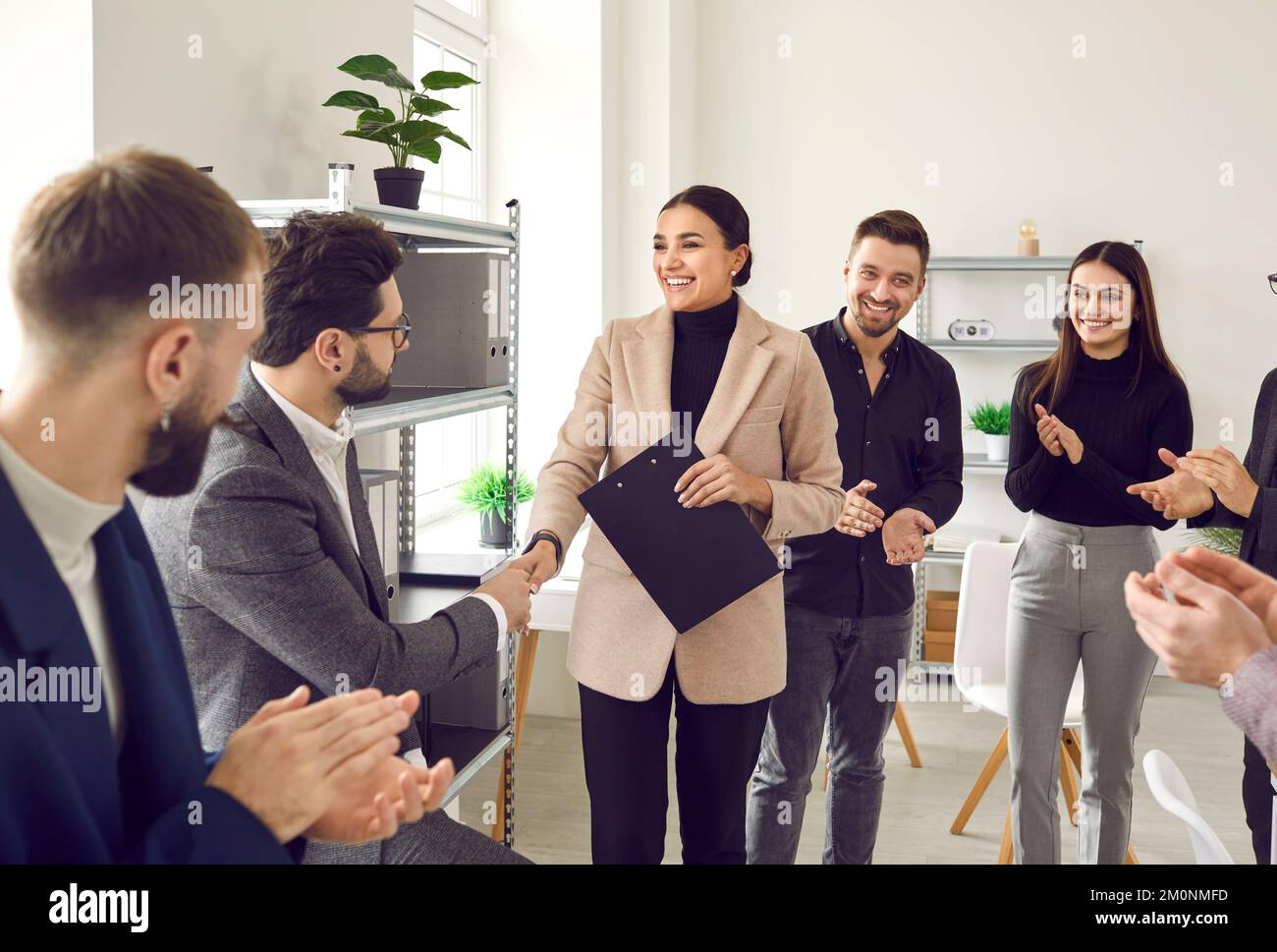 Friendly female manager shakes hands with her male colleague ...