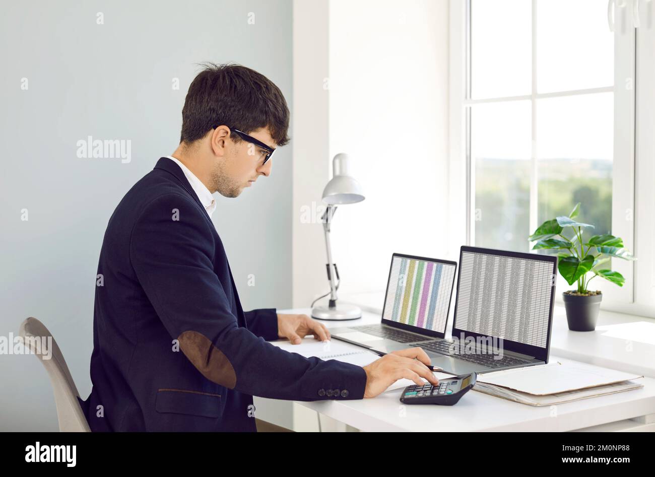 Man office worker is working with spreadsheets on computers screens and ...