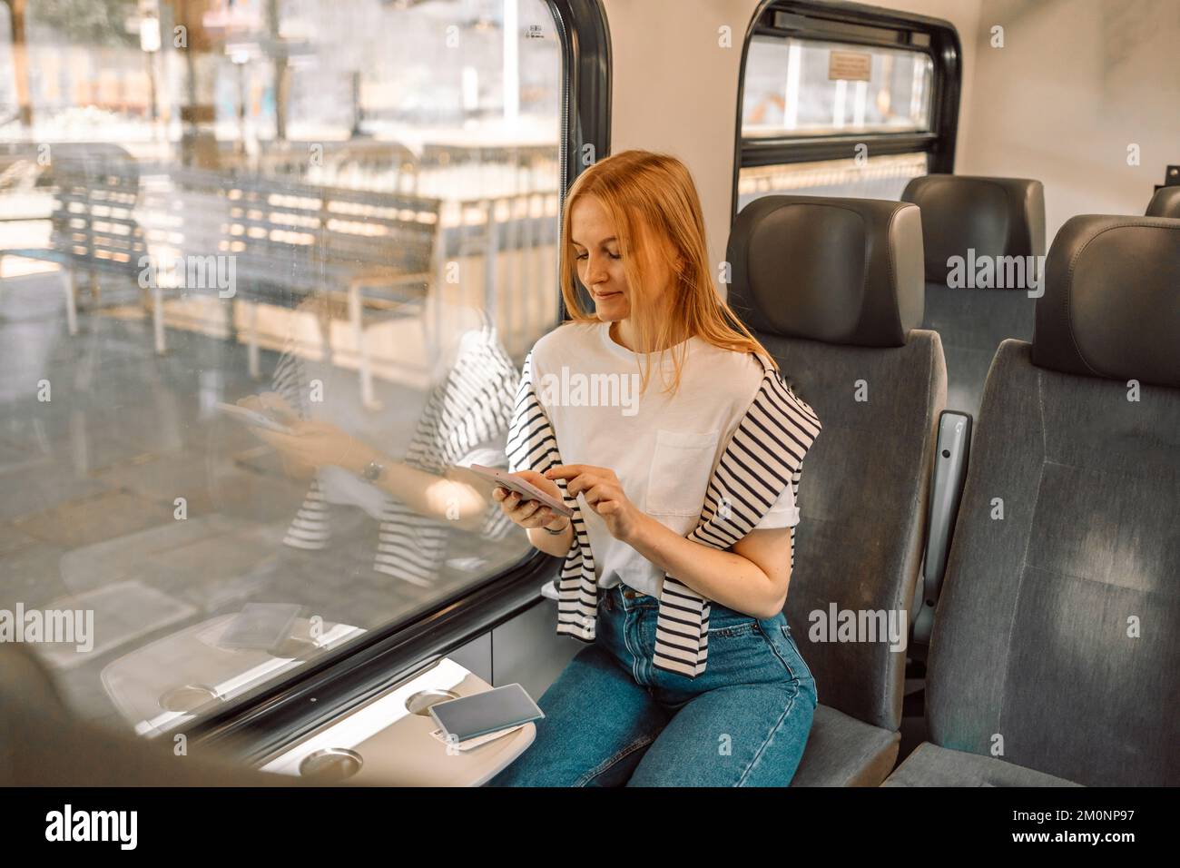 Portrait of a smiling lovely girl typing message on mobile phone in ...