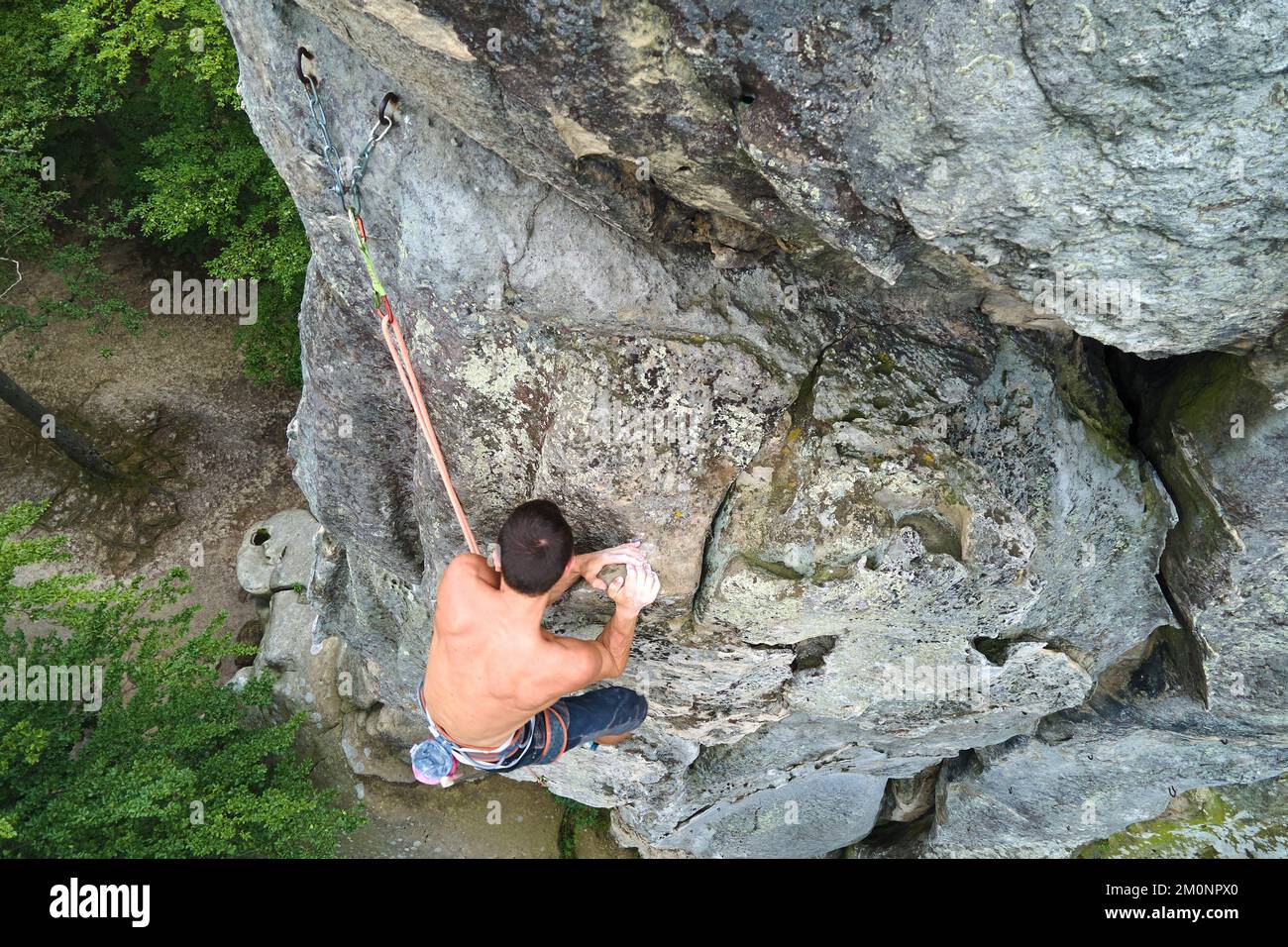 Determined climber clambering up steep wall of rocky mountain ...