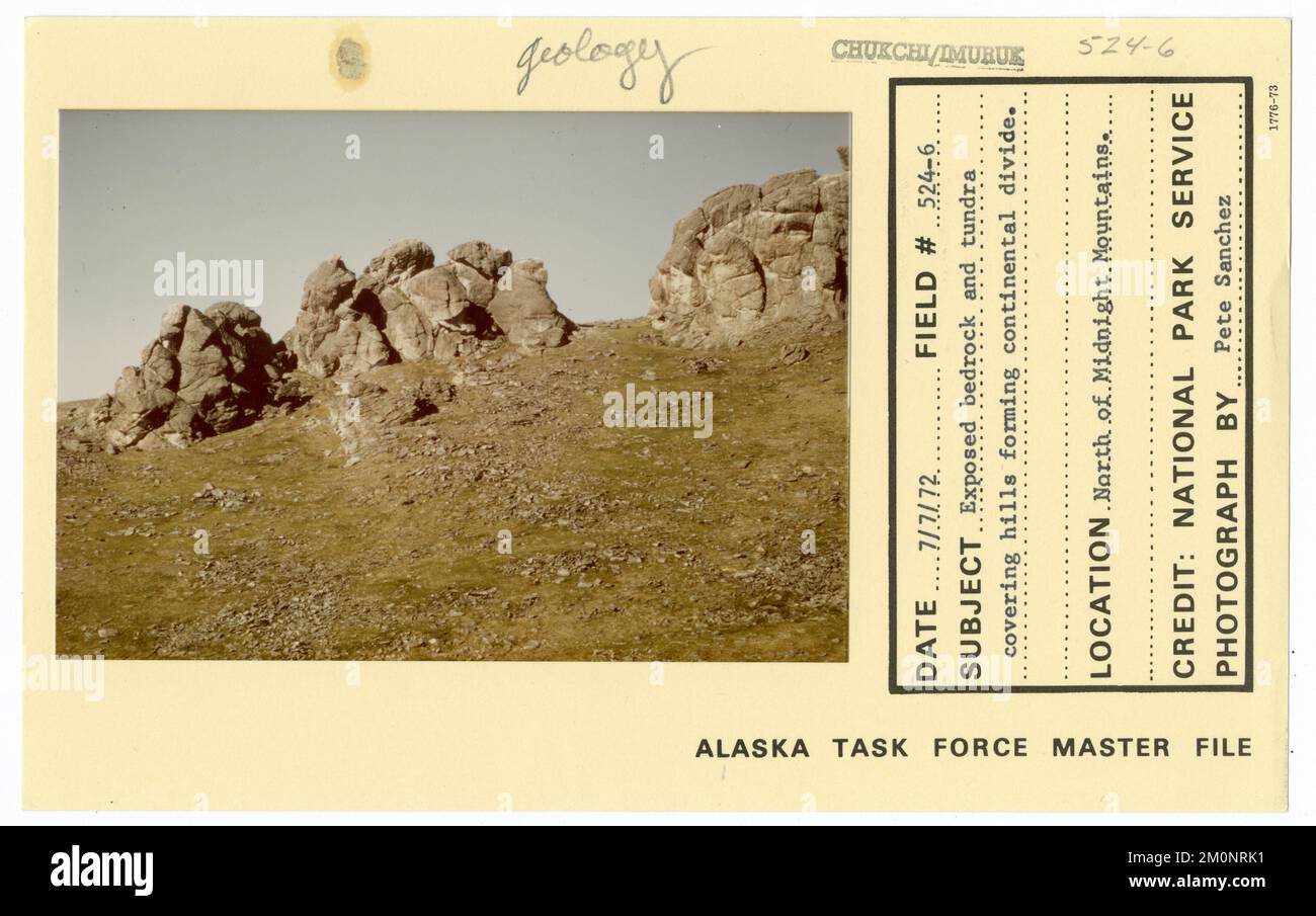 Exposed bedrock and tundra covering hills forming continental divide ...