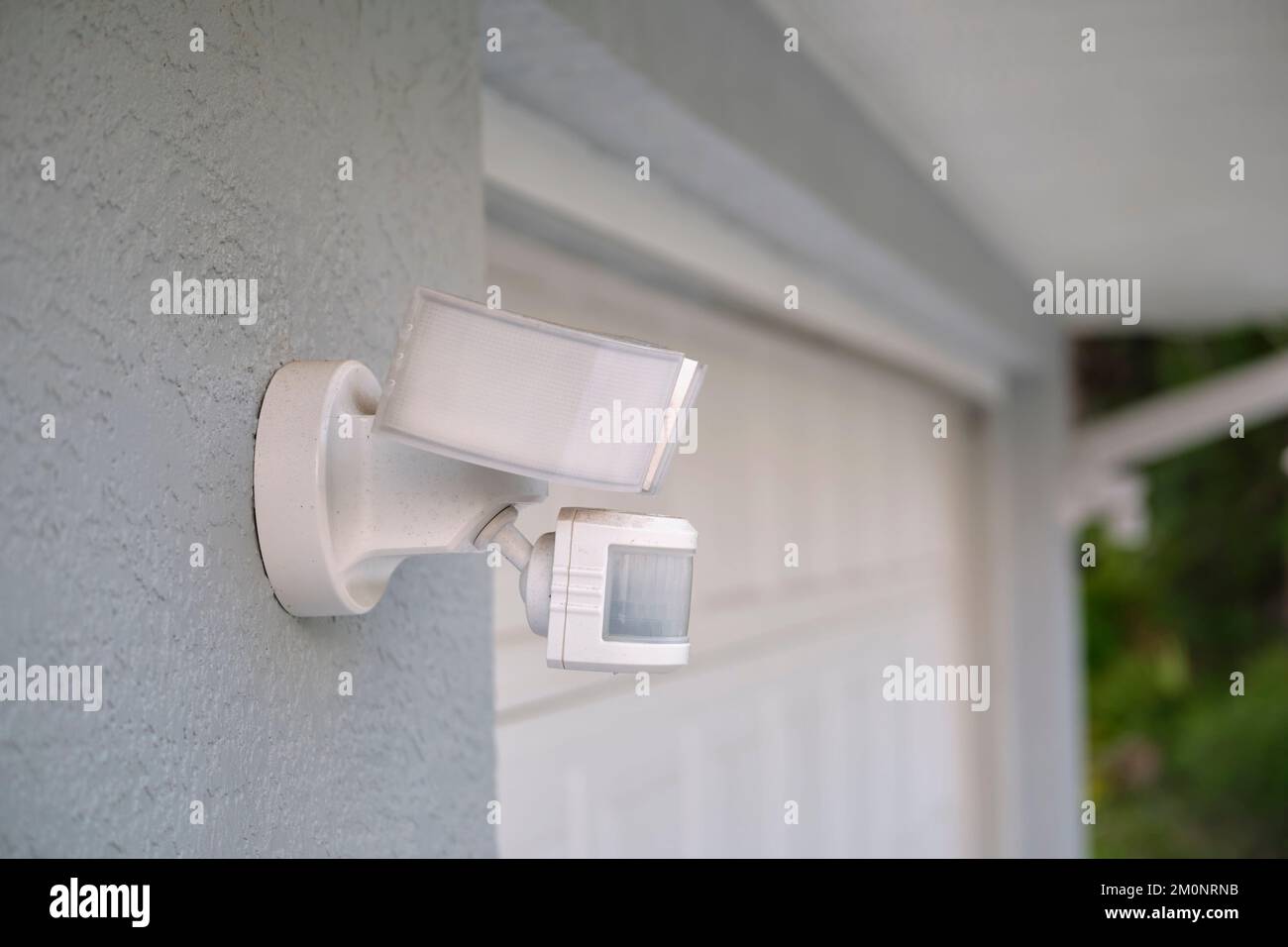Motion sensor with light detector mounted on exterior wall of private ...