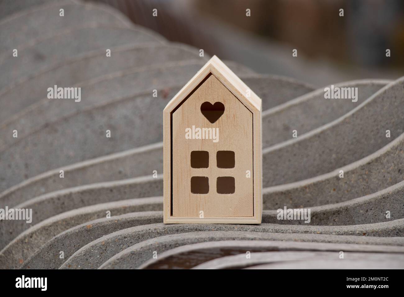 A small wooden house stands on a striped wavy stone background, a dream ...