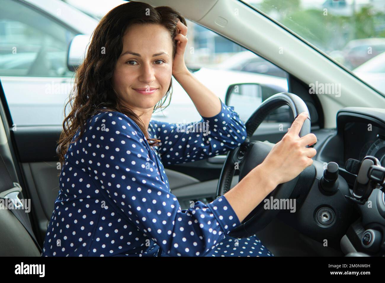 Young stylish woman driver sitting behind steering wheel of her car ...