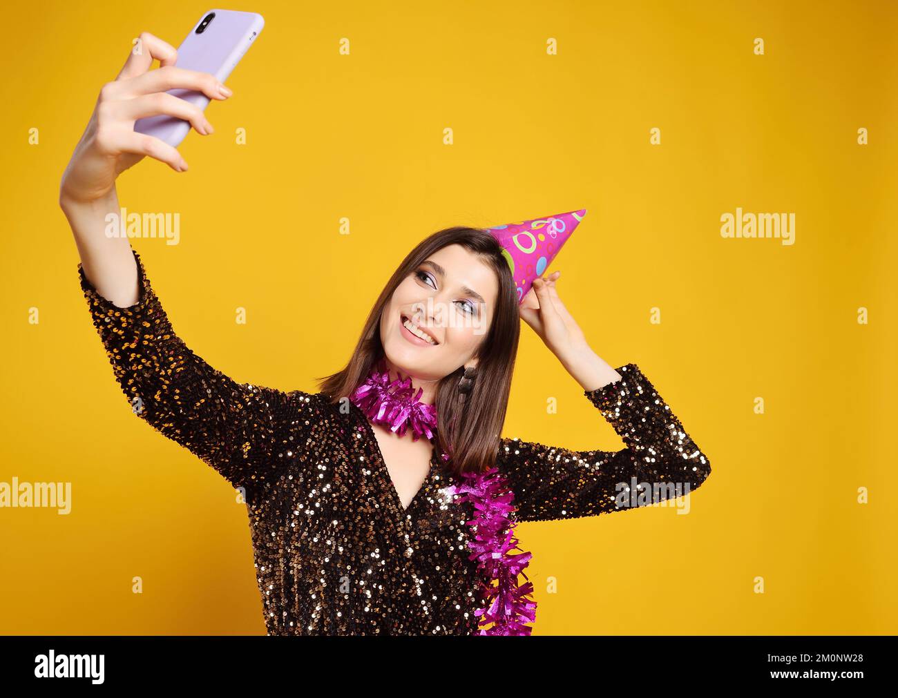 young woman in a pink party hat and with a pink boa around her neck ...