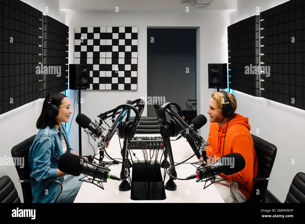 Happy young asian woman and white man using microphone and headphones ...