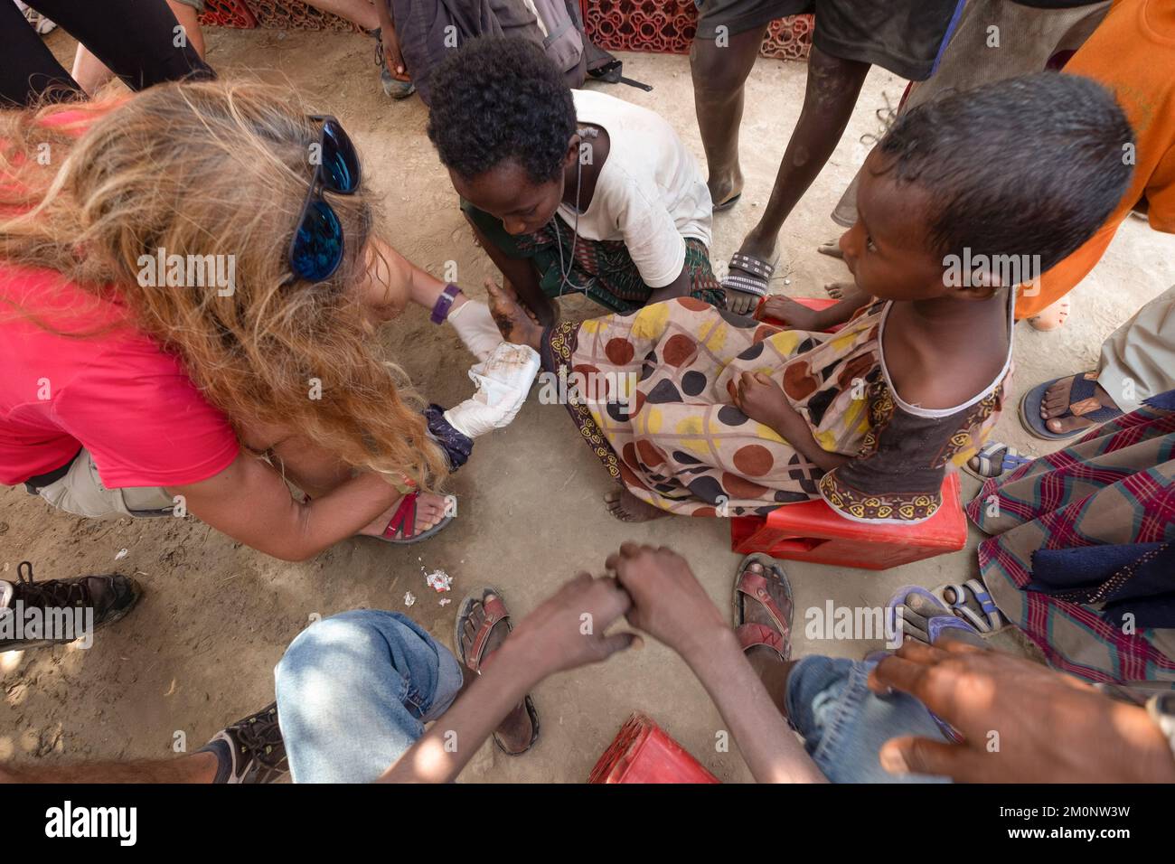 The Caucasian doctor treats the injured foot of the black African girl ...