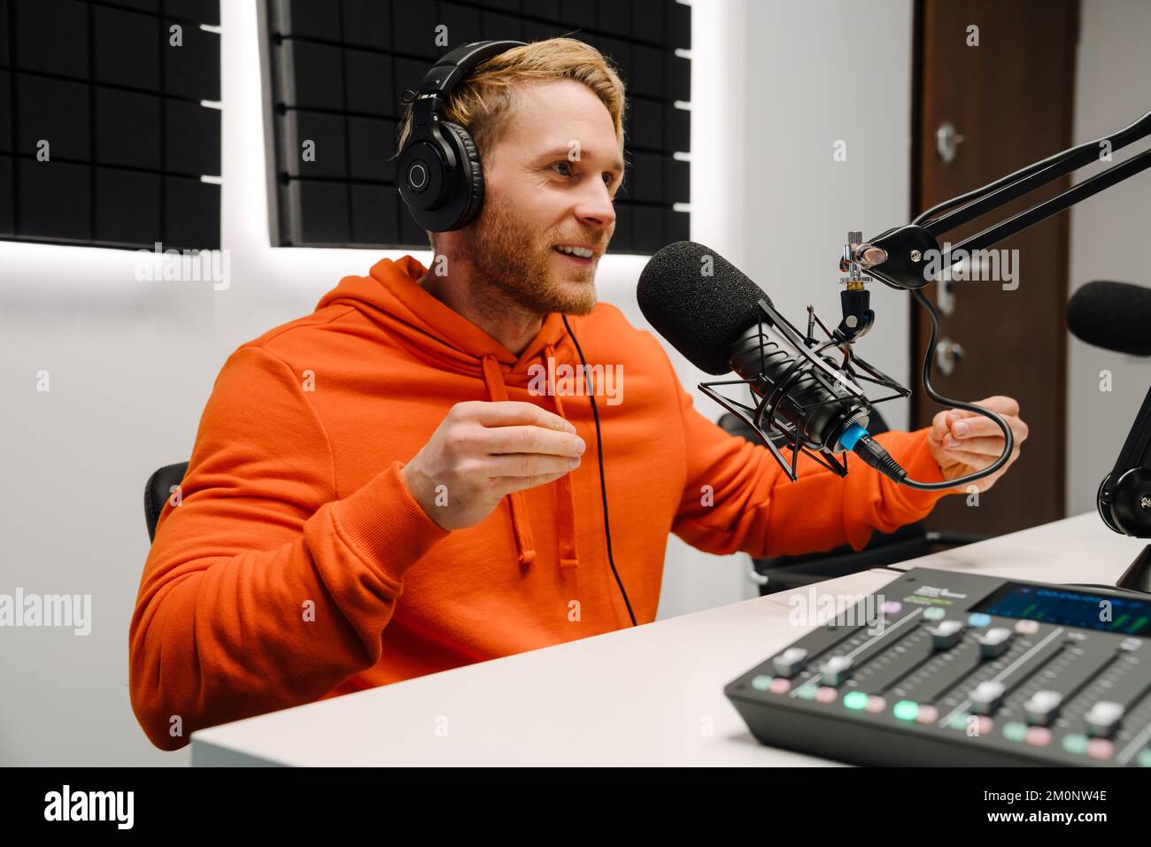 Happy young male radio host using microphone and headphones while ...