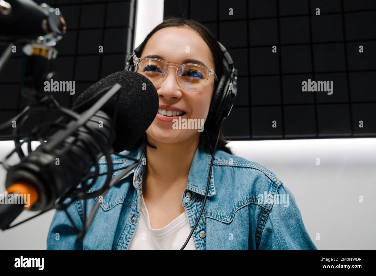 Beautiful happy young female radio host using microphone and headphones ...