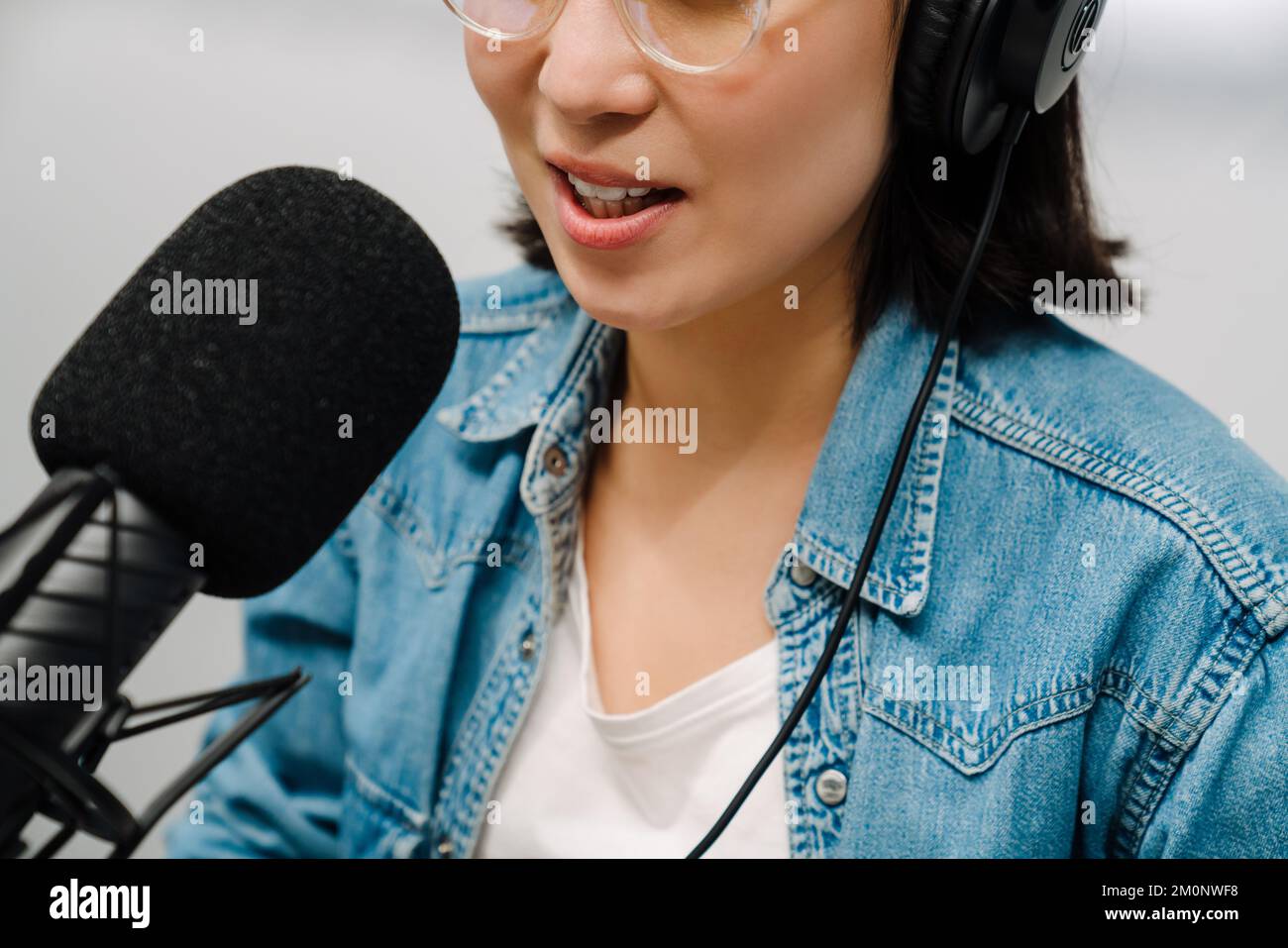 Beautiful happy young female radio host using microphone and headphones ...