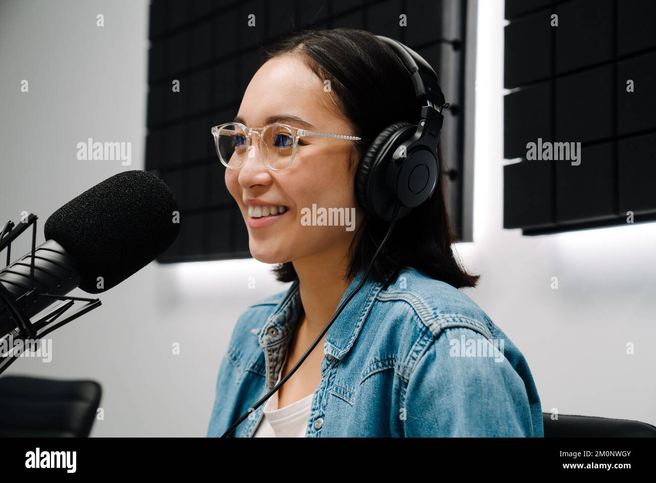 Beautiful happy young female radio host using microphone and headphones ...