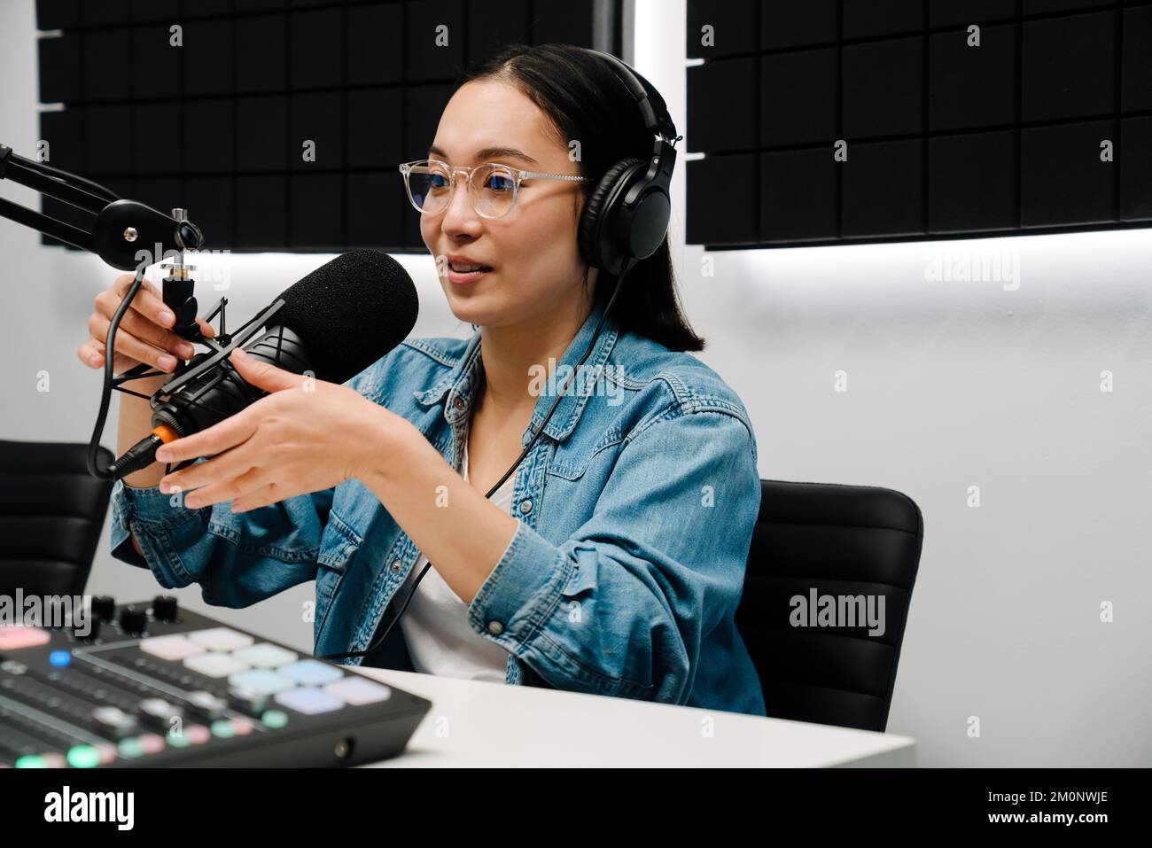 Beautiful happy young female radio host using microphone and headphones ...