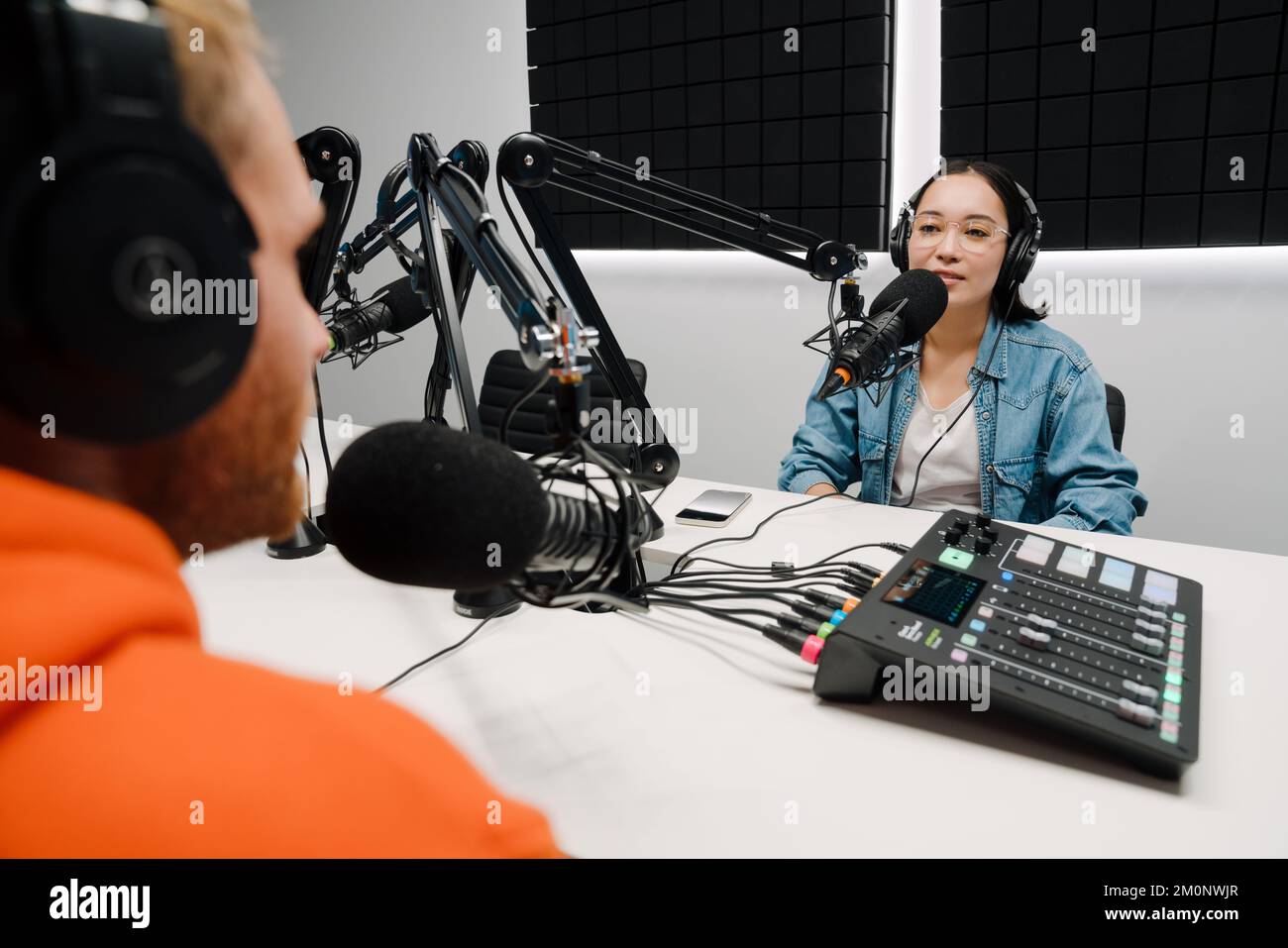 Happy young asian woman and white man using microphone and headphones ...