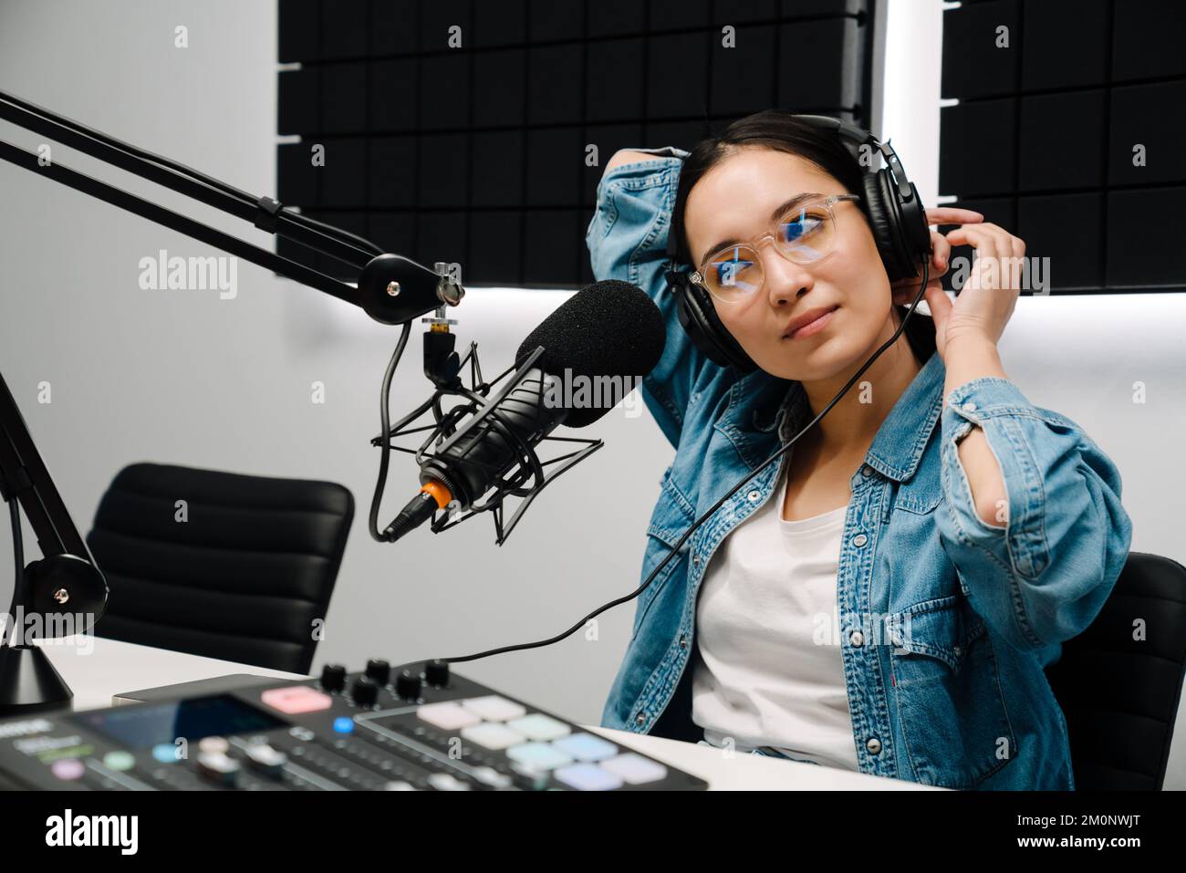 Beautiful happy young female radio host using microphone and headphones ...