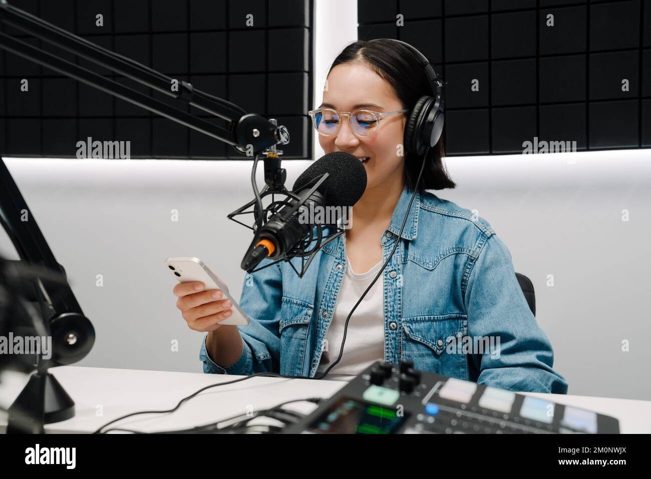 Beautiful happy young female radio host using microphone and headphones ...