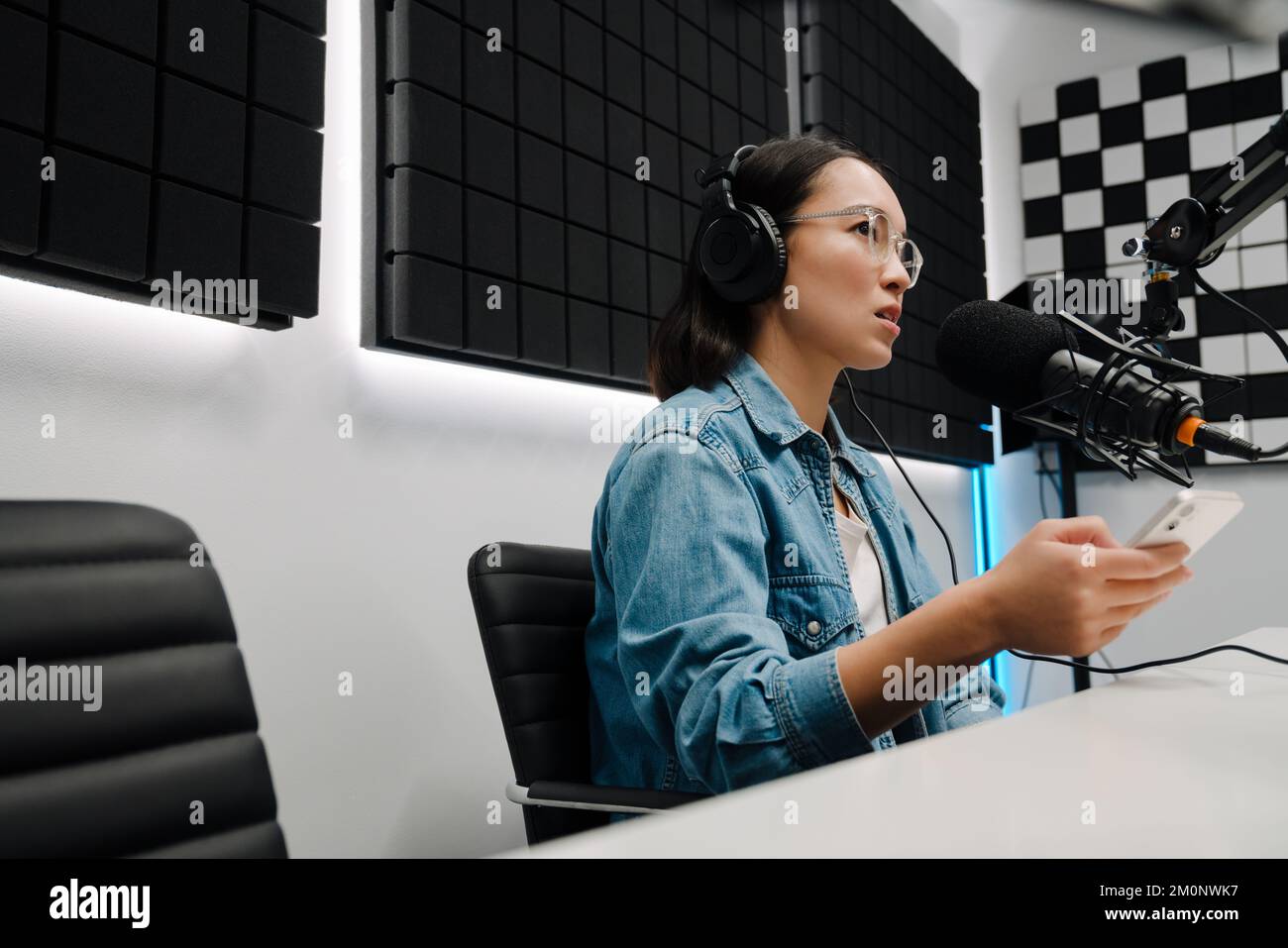 Beautiful happy young female radio host using microphone and headphones ...