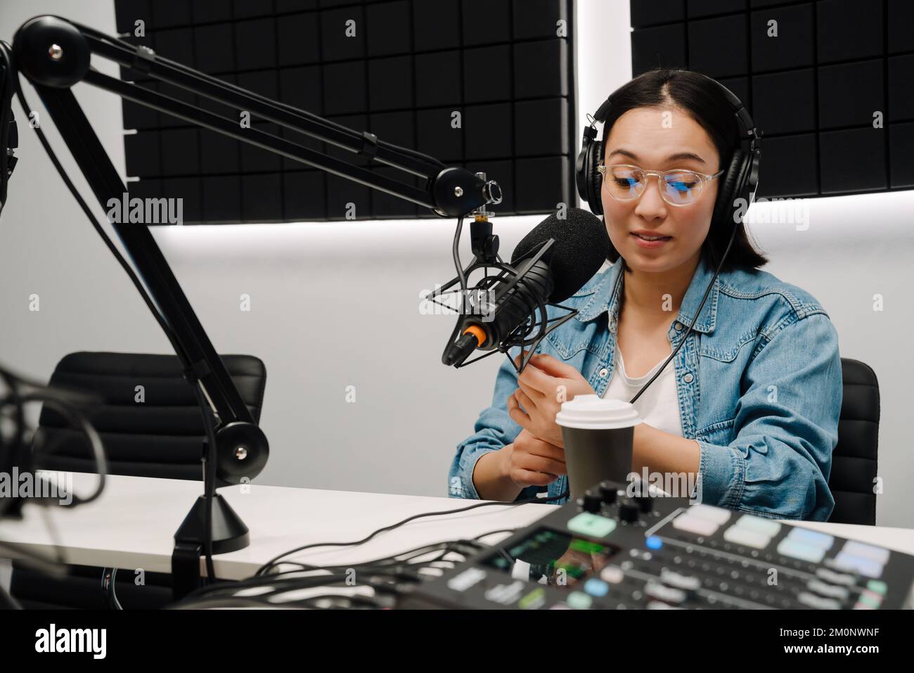 Beautiful happy young female radio host using microphone and headphones ...