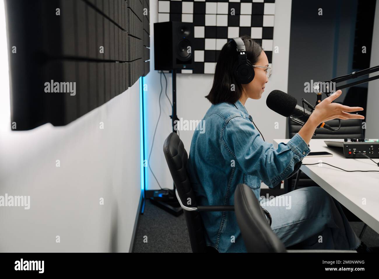 Beautiful happy young female radio host using microphone and headphones ...