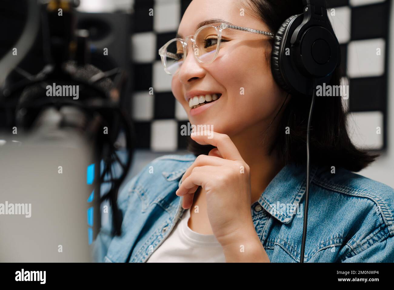 Beautiful happy young female radio host using microphone and headphones ...