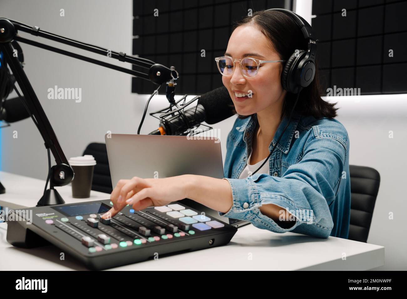 Beautiful happy young female radio host using microphone and sound ...