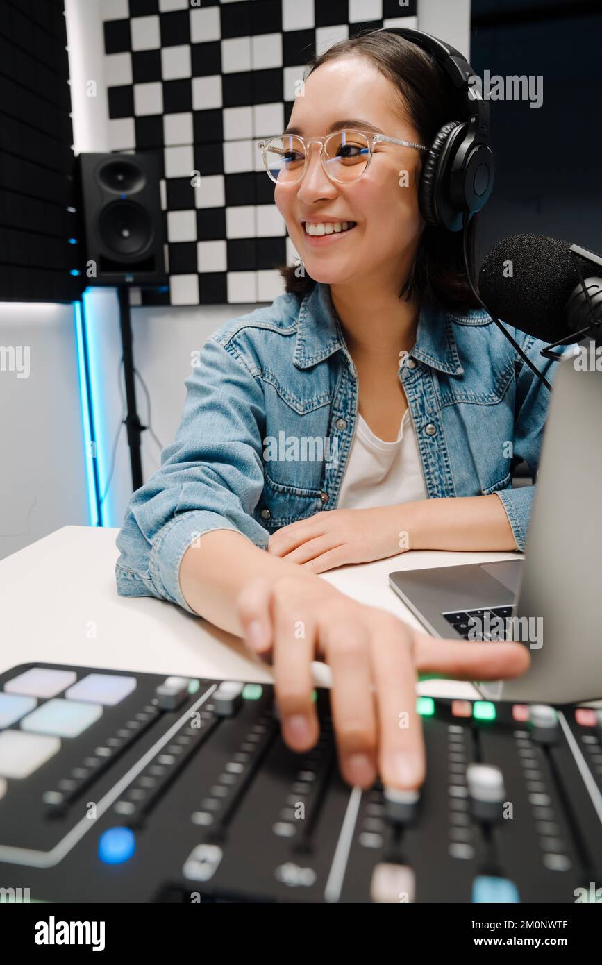 Beautiful happy young female radio host using headphones and sound ...