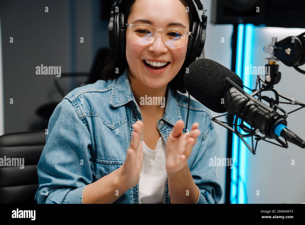 Beautiful happy young female radio host using microphone and headphones ...