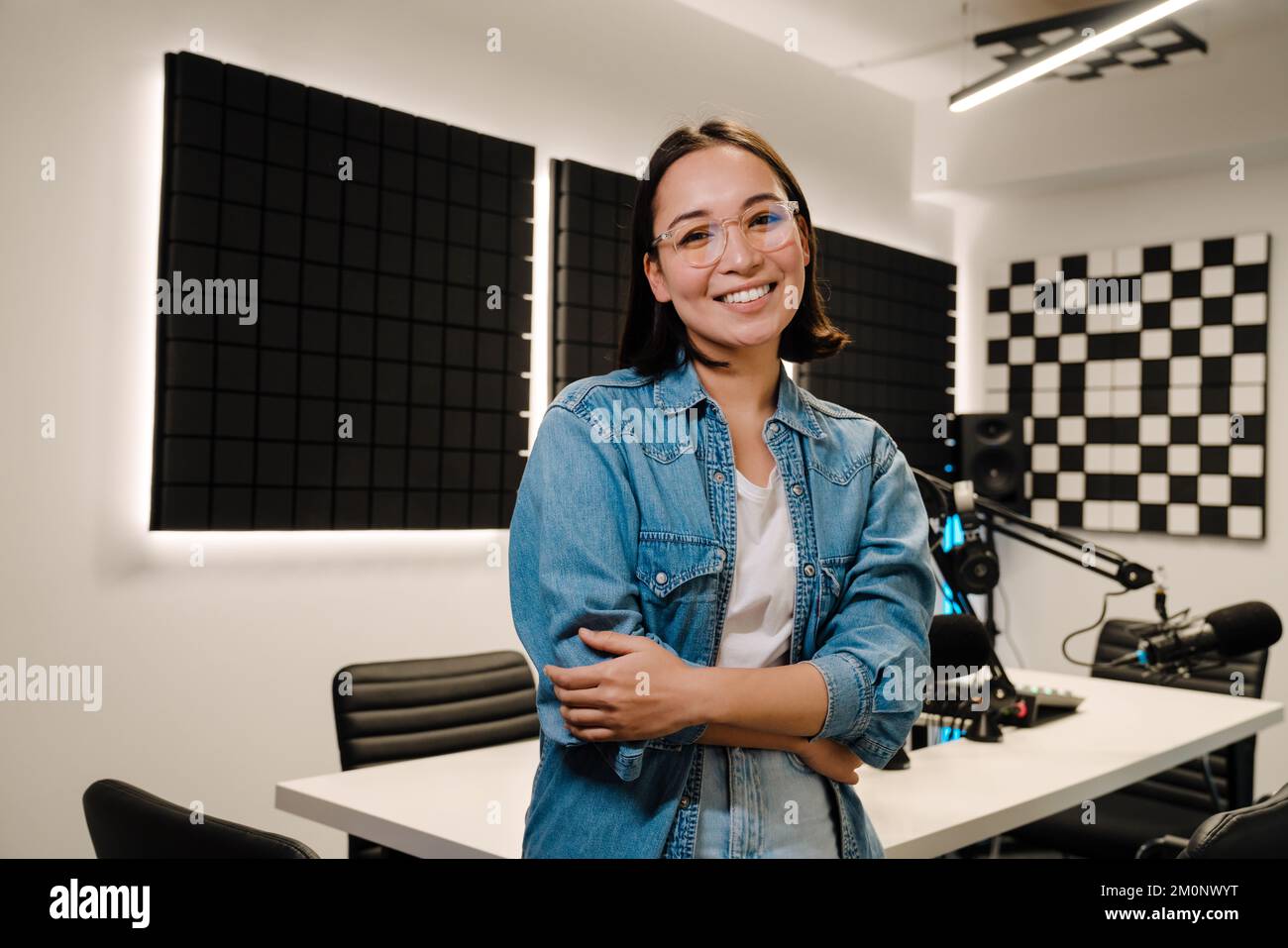 Beautiful happy young female radio host smiling while broadcasting in ...