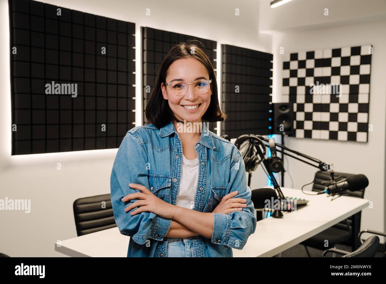 Beautiful happy young female radio host smiling while broadcasting in ...