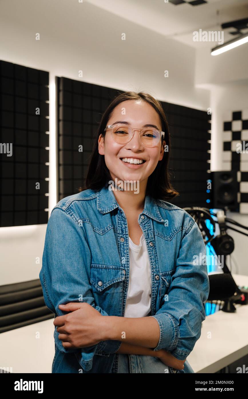 Beautiful happy young female radio host smiling while broadcasting in ...