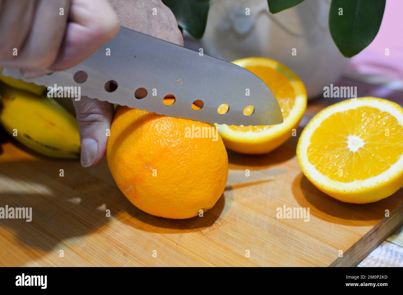 A female hands cutting an orange in half with a sharp knife Stock Photo ...