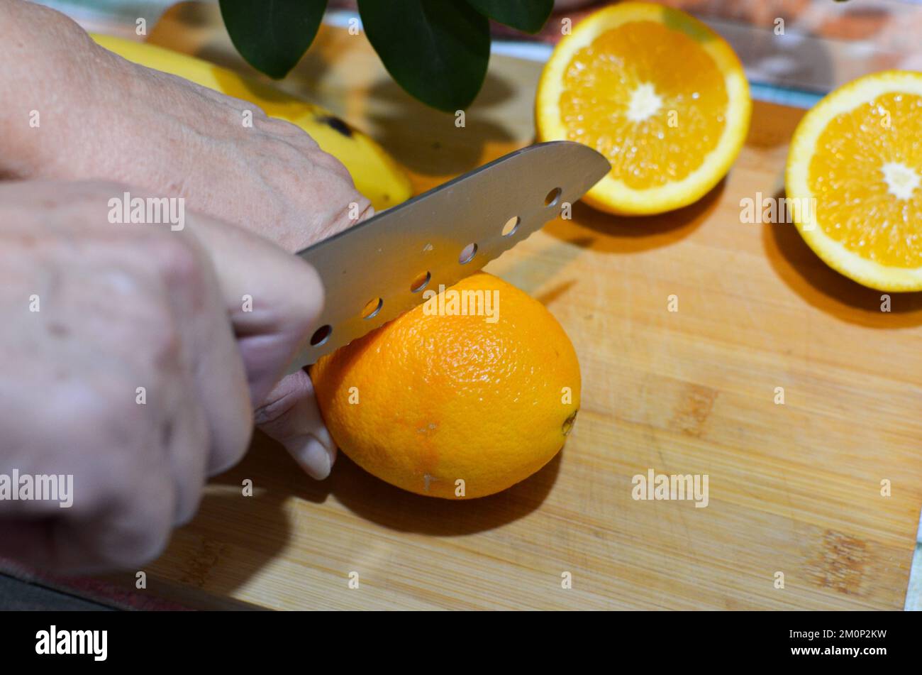 A female hands cutting an orange in half with a sharp knife Stock Photo ...