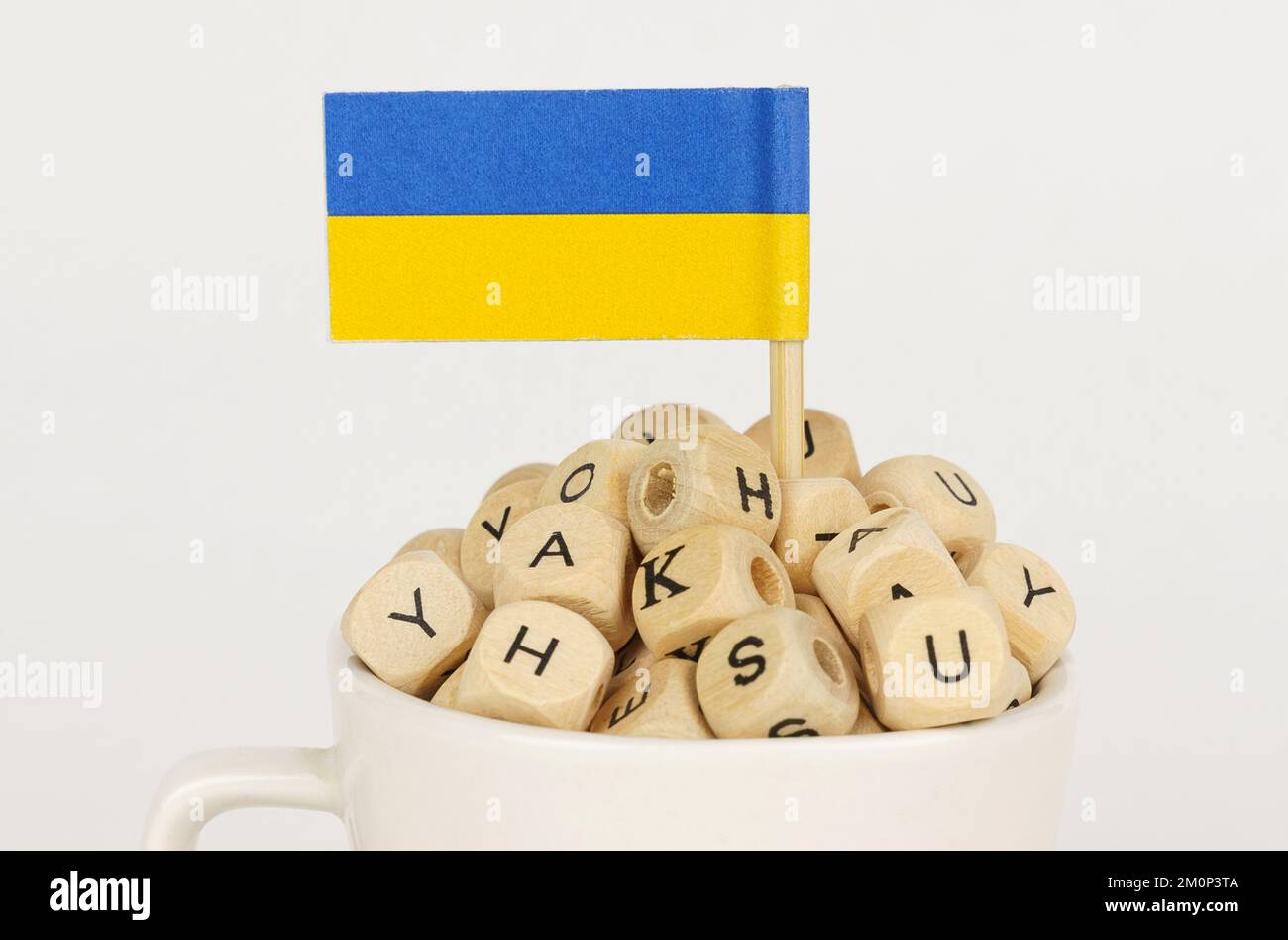 The flag of Ukraine sticks out of a cup with cubes on which letters are ...