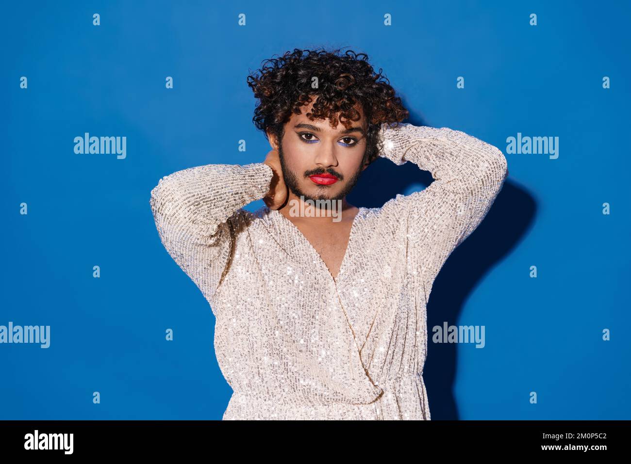 Young curly man with makeup posing and looking at camera isolated over ...