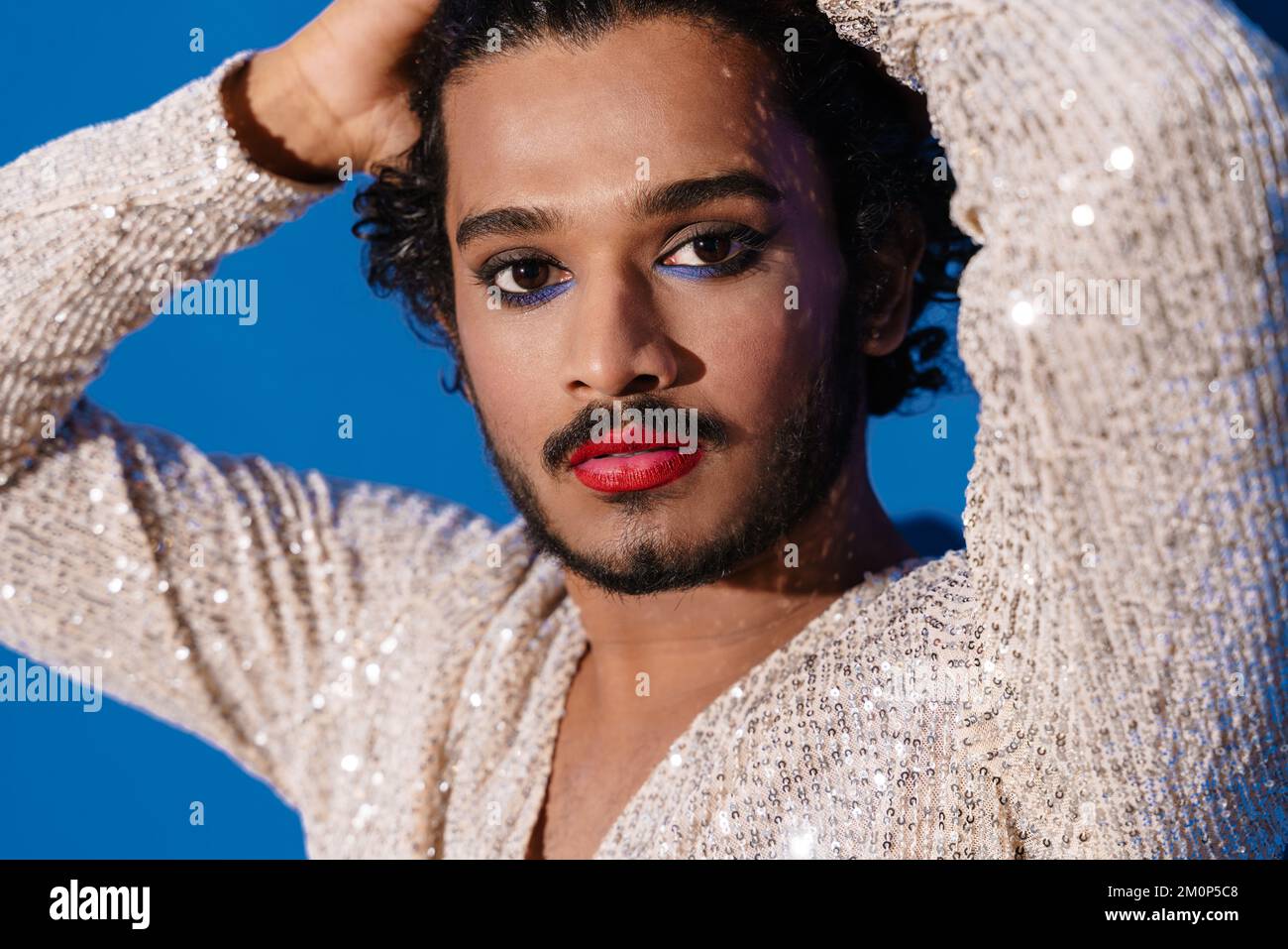 Young curly man with makeup posing and looking at camera isolated over ...