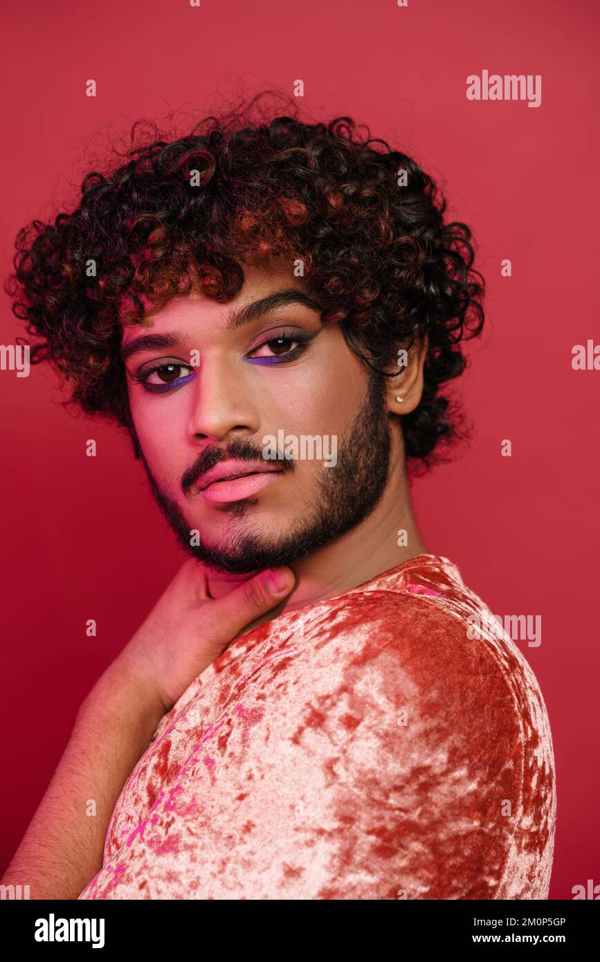 Young curly man with makeup posing and looking at camera isolated over ...