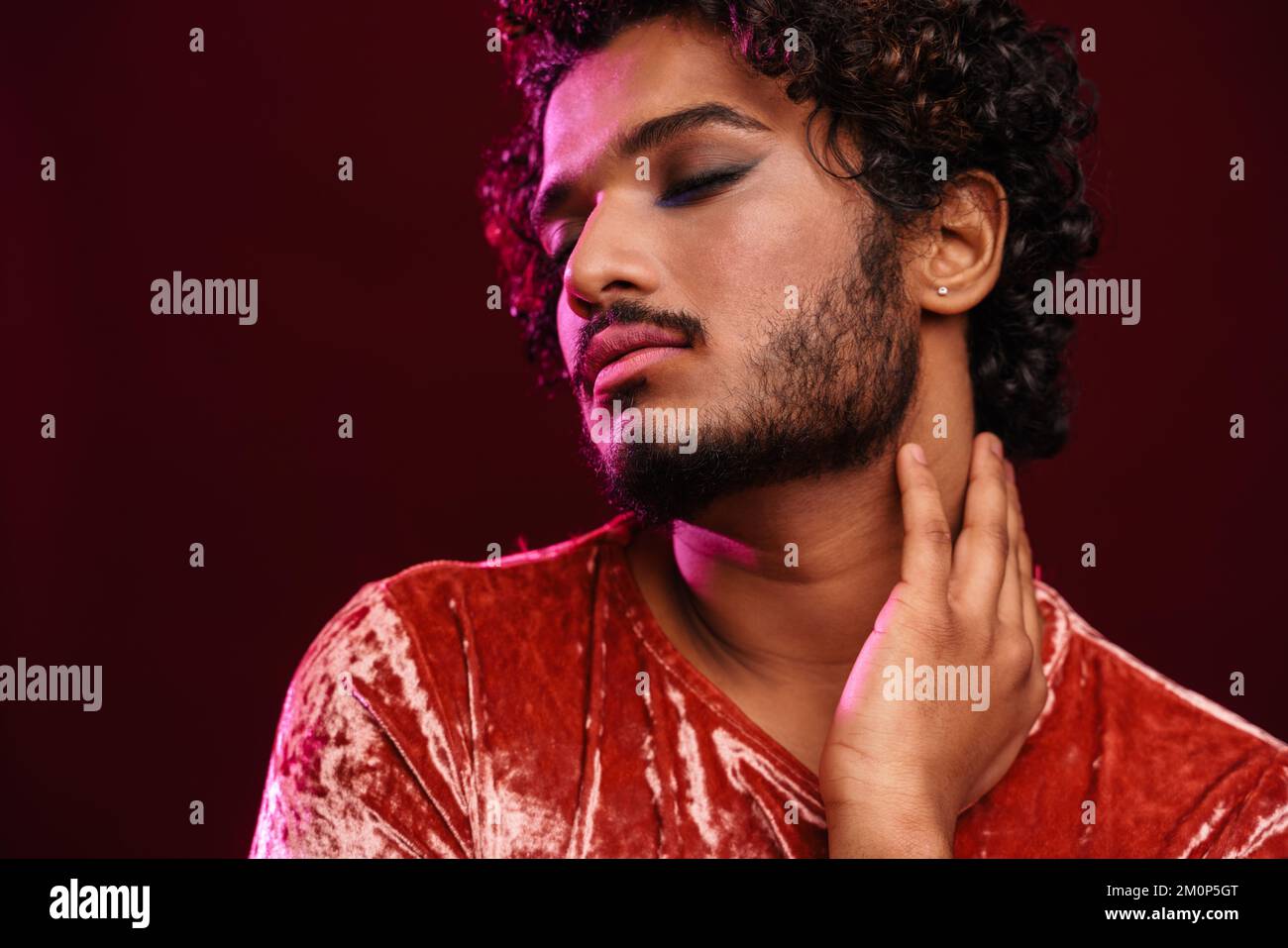 Young curly man wearing velvet t-shirt posing with eyes closed isolated ...