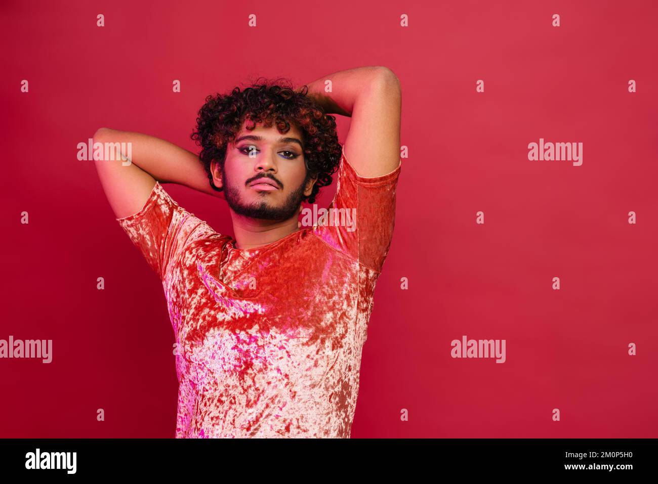 Young curly man with makeup posing and looking at camera isolated over ...