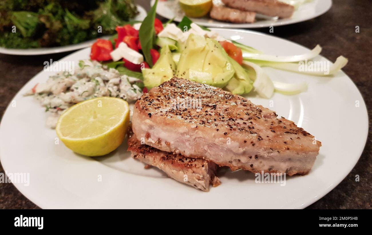 A closeup of freshly cooked tuna with salad and avocado on a plate on ...
