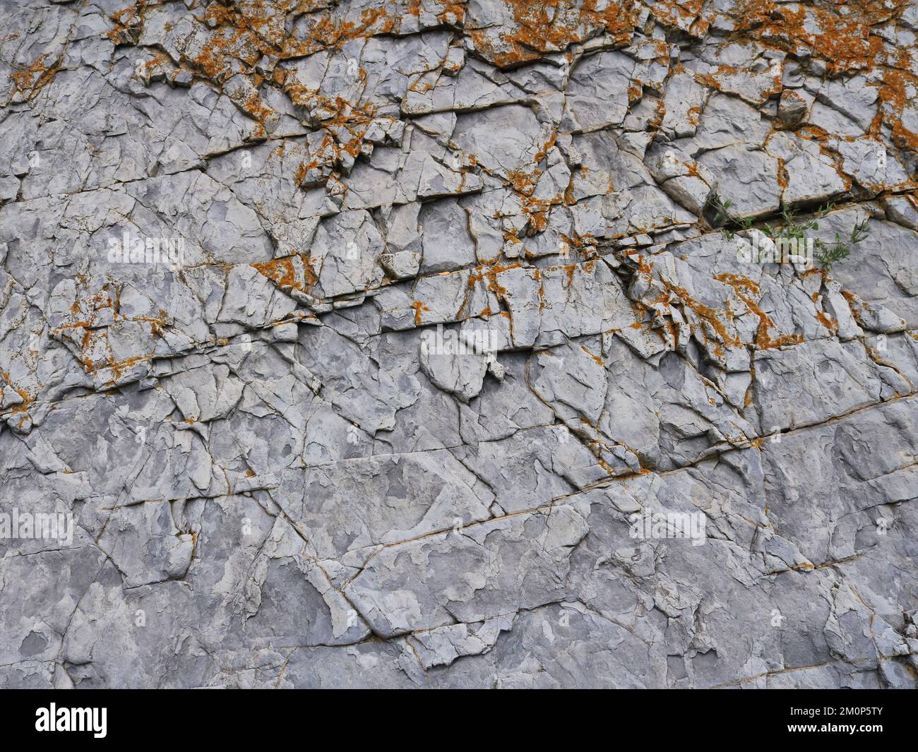 a fragment of a rocky gray textured mountain surface with rusty patches ...