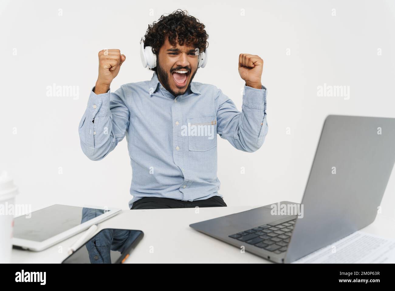Young indian glad office employee employee sitting in front of laptop ...