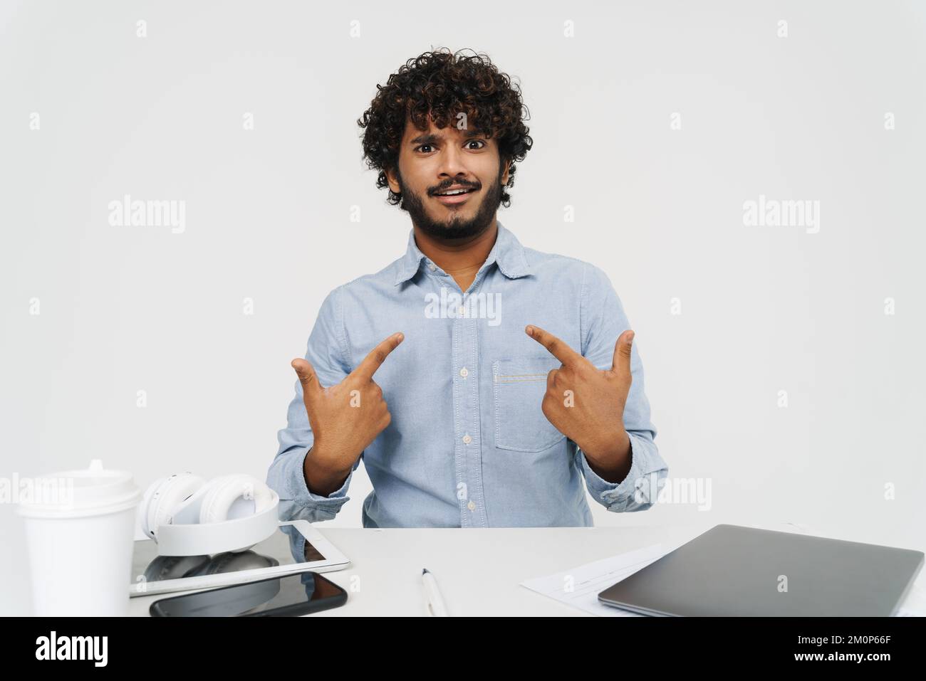 Adult indian office employee is pointing on himself by office table ...