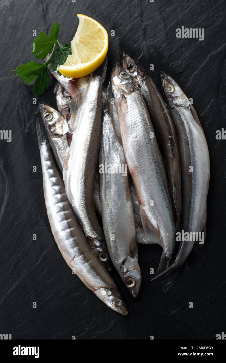 Freshly caught small marine fish on a plate on a gray concrete ...