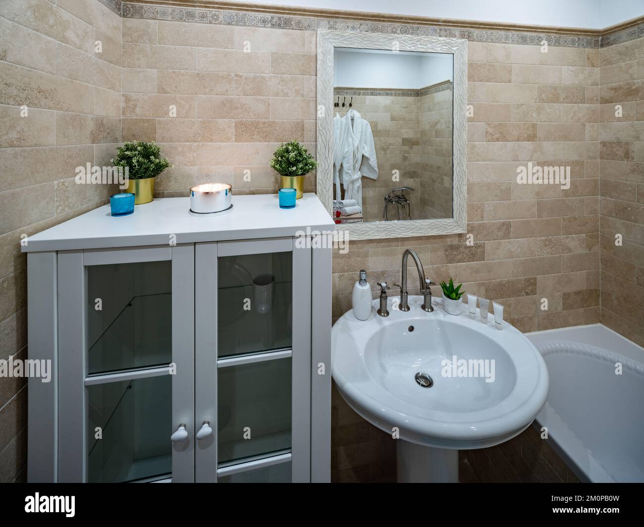 Bathroom interior. White sink and mirror. Empty locker. Beige tile ...