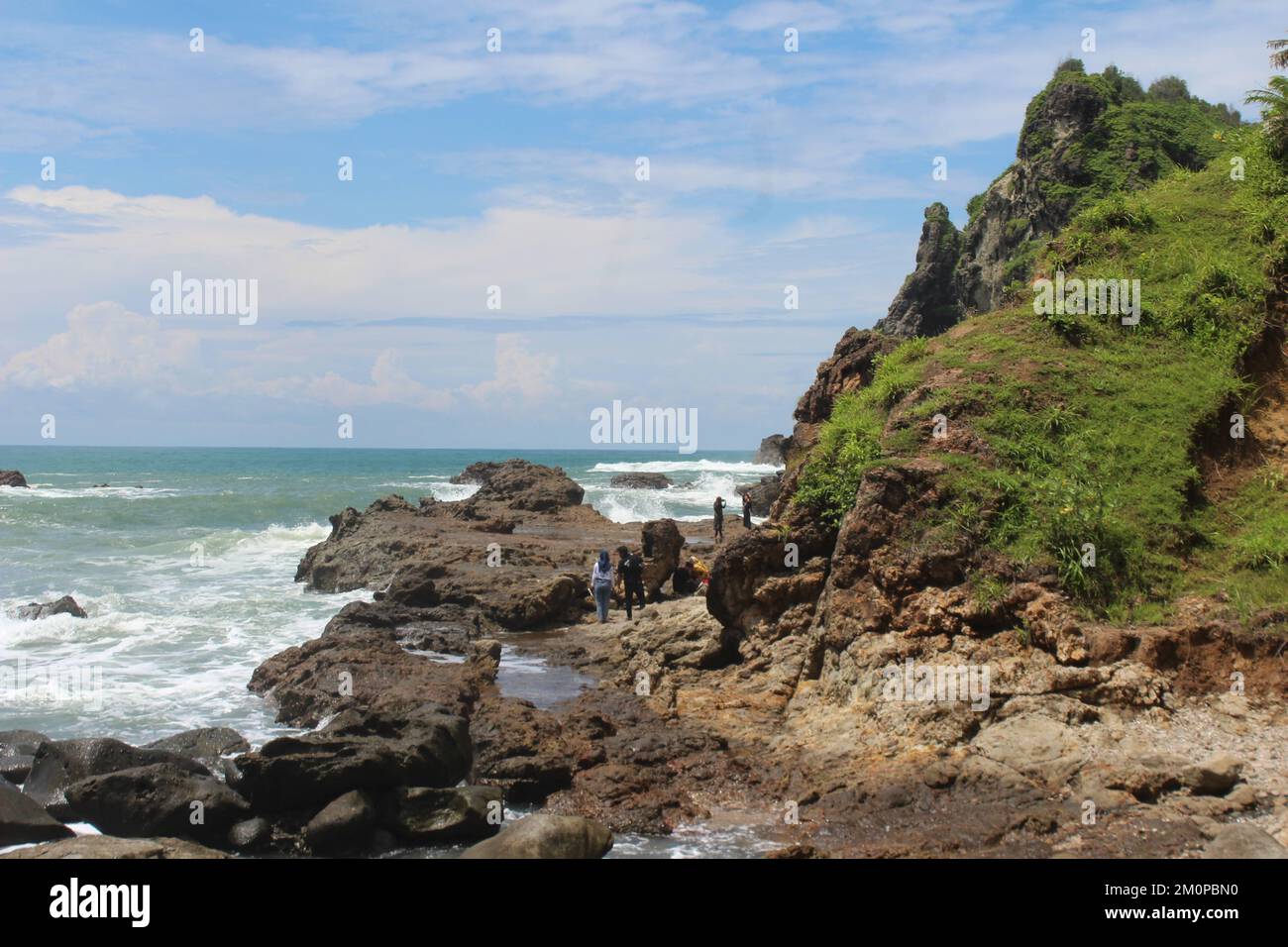 A beautiful shot of people on a rocky coastline in the daytime Stock ...